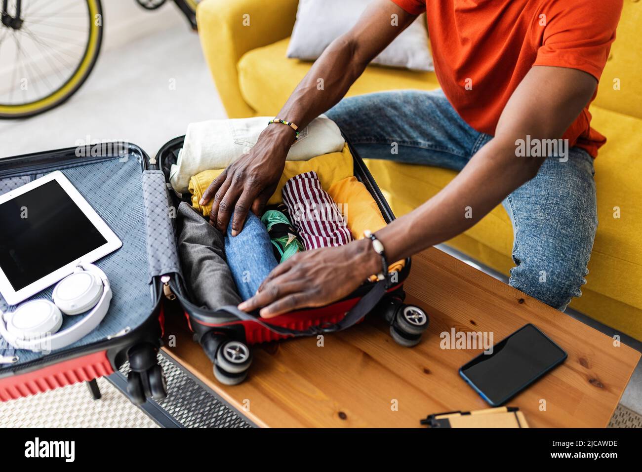 Close up hands of young african man packing luggage before going on ...