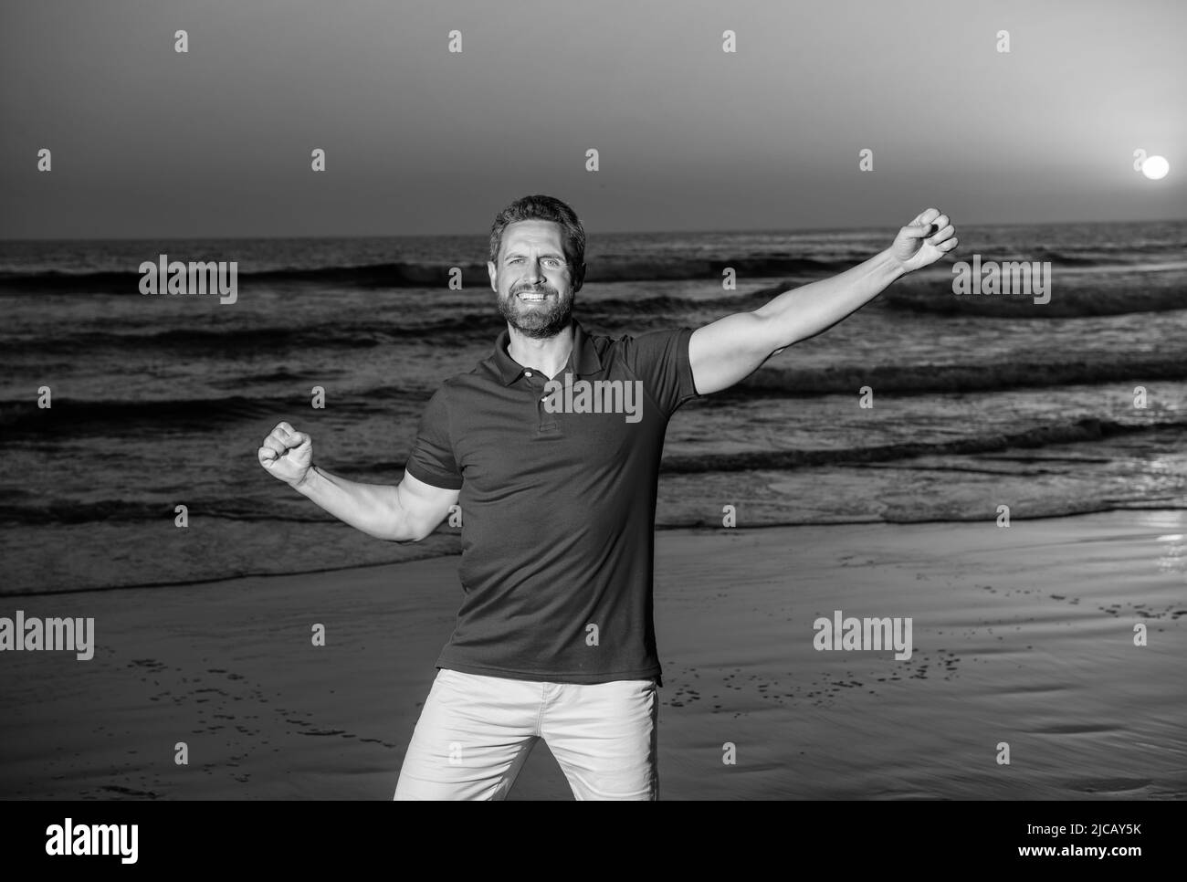 happy man celebrating success over the sea on sunsdown summer beach ...