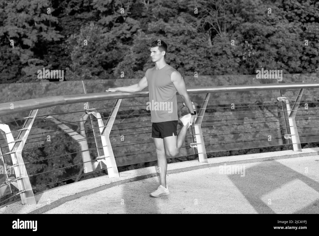 Athletic guy in sportswear grab ankle with hand stretching leg after ...