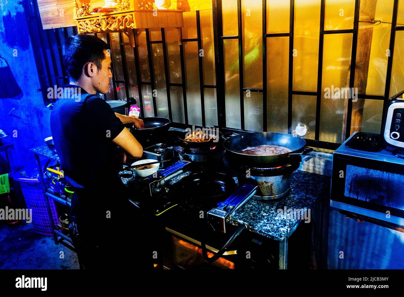 The chef watches as the food he is cooking in the pans are about done ...