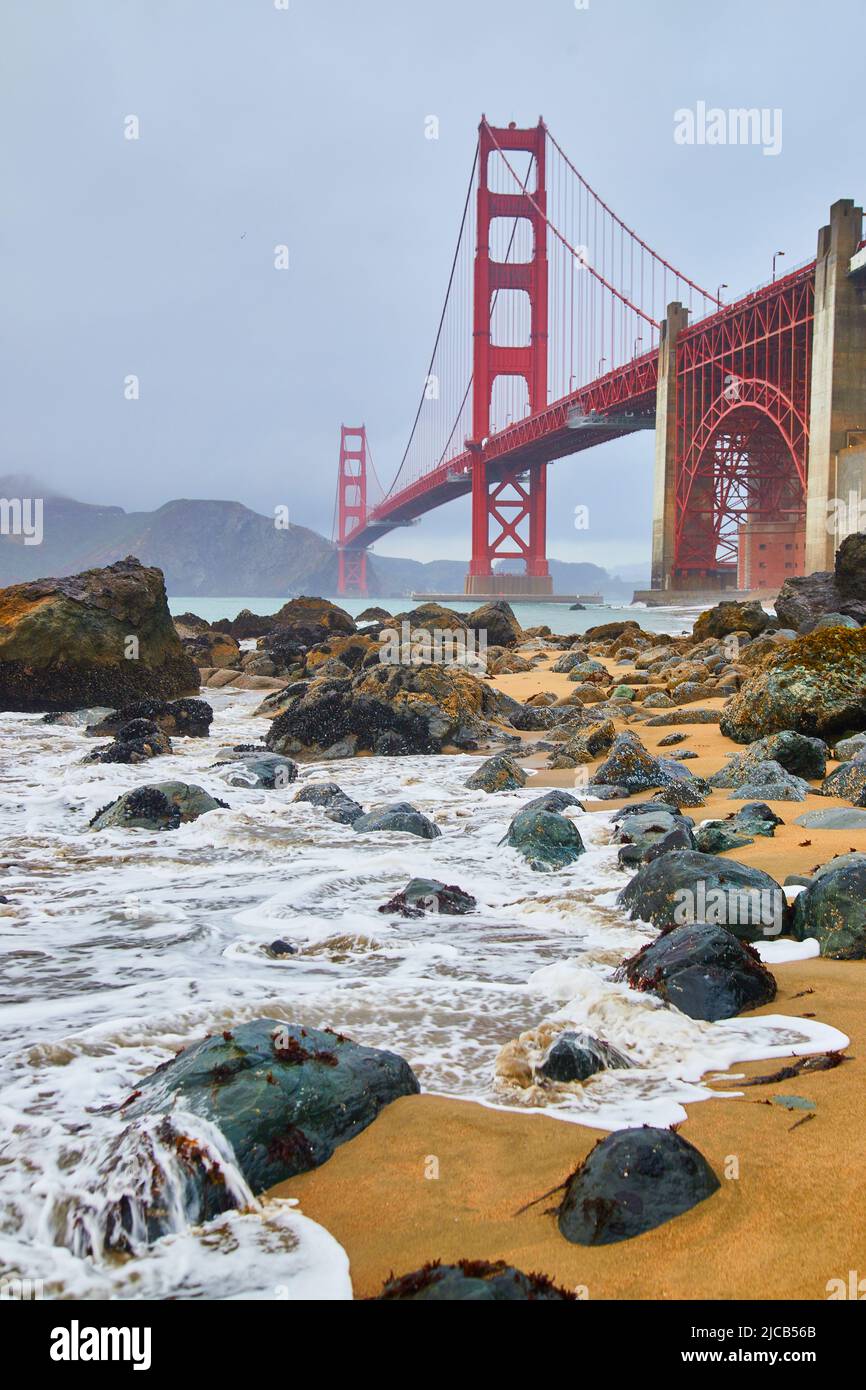Ocean waves crashing on sandy beach by Golden Gate Bridge on foggy ...