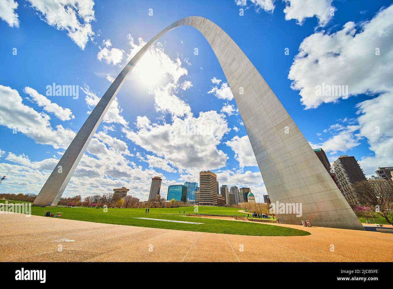 Skyline viewed under St. Louis Gateway Arch with vibrant sky and sun ...