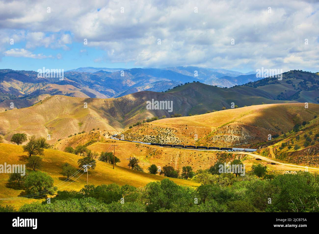 Lush spring mountain landscape with green trees and train on tracks ...