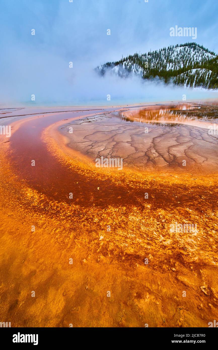 Red and orange spiral in spring of Yellowstone by winter mountains ...