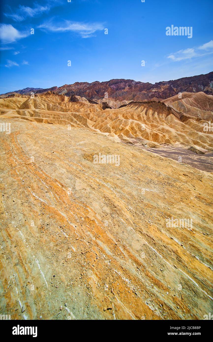 Layers of colorful rock next to waves of sediment formations in desert ...