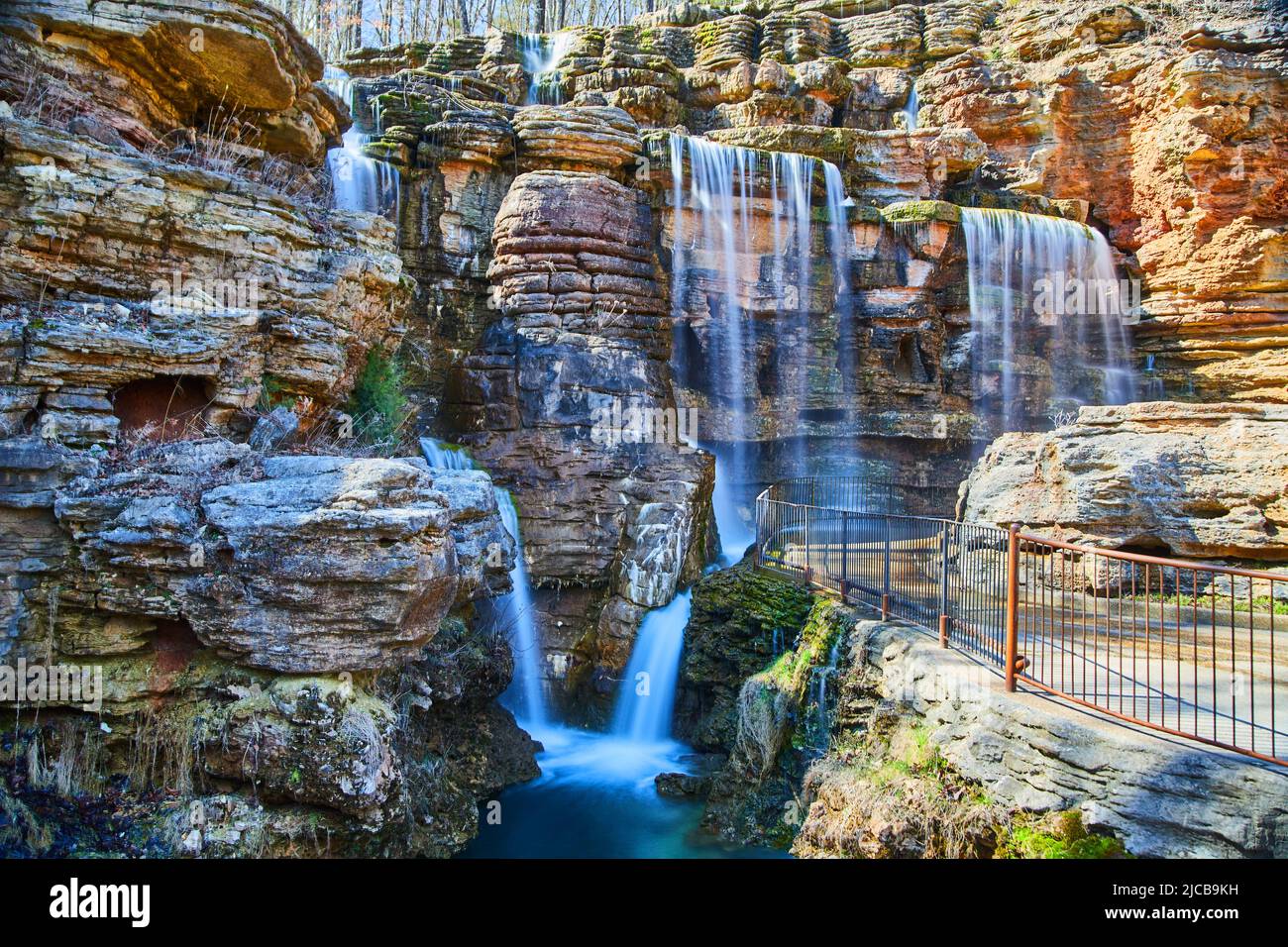 Multiple waterfalls pouring over cliffs into river by paved path Stock ...
