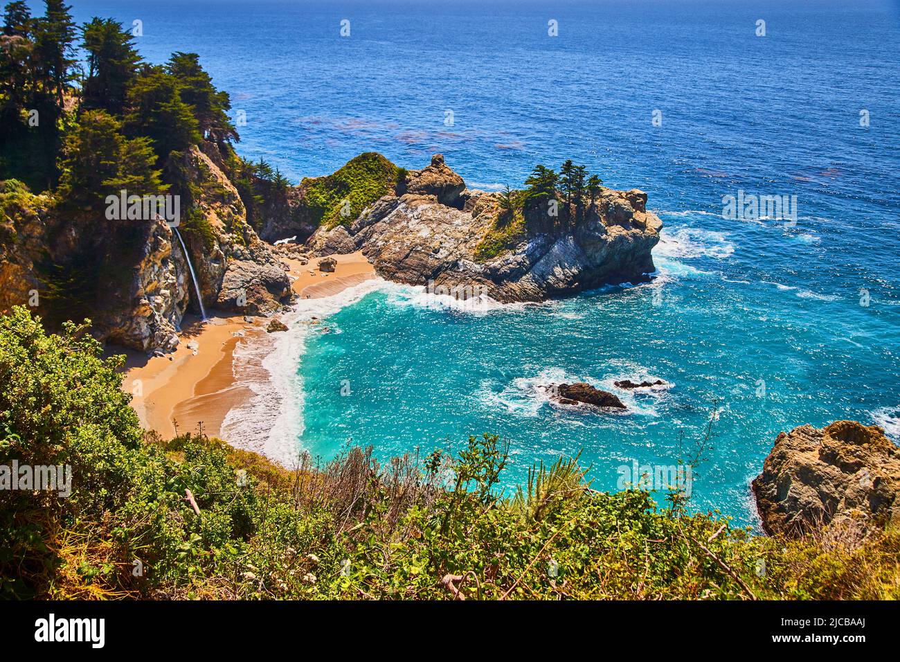 Small ocean cove surrounded by cliffs, waterfall, and sandy beaches ...