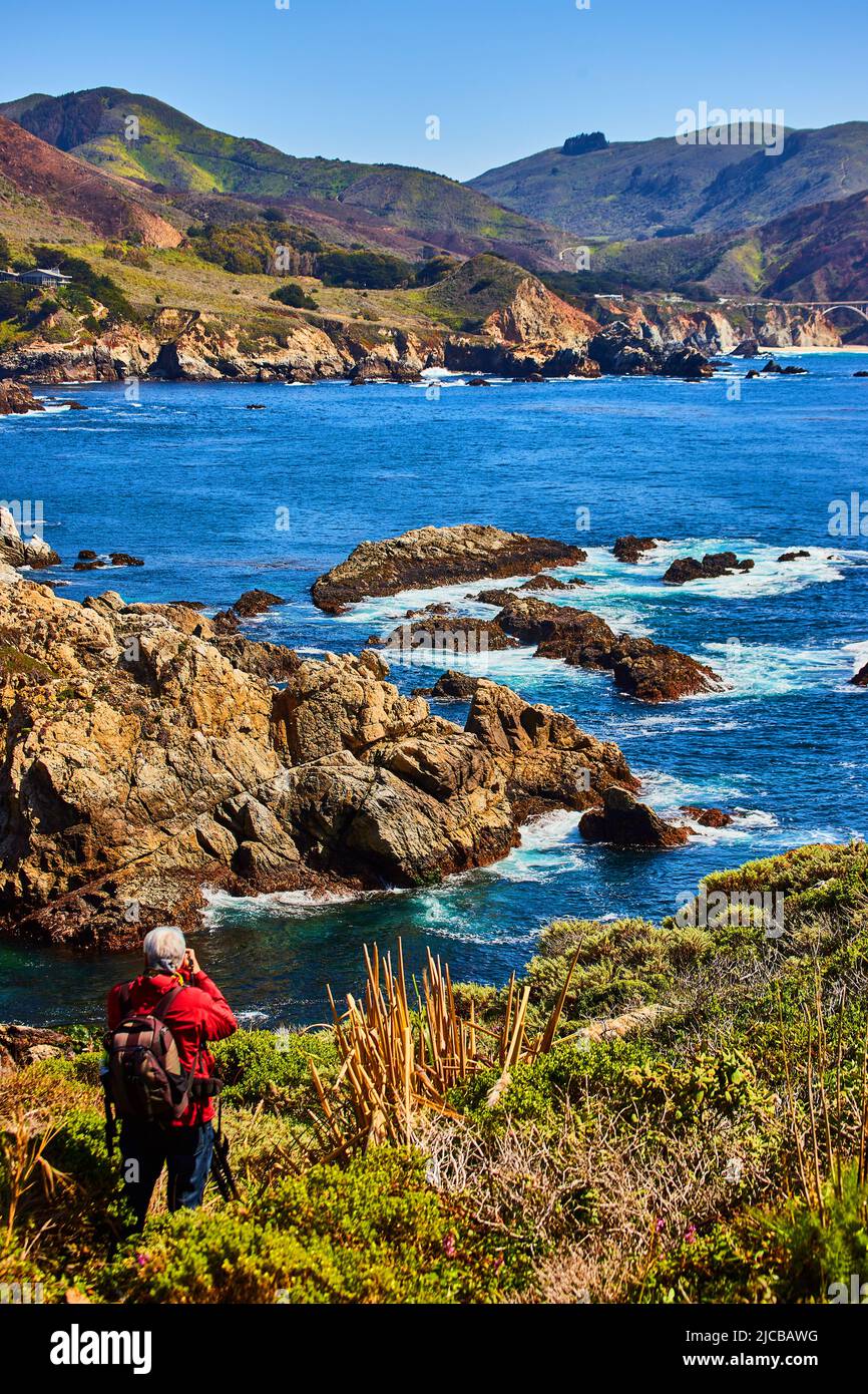Old photographer capturing beautiful west coast cliffs and bridge in ...