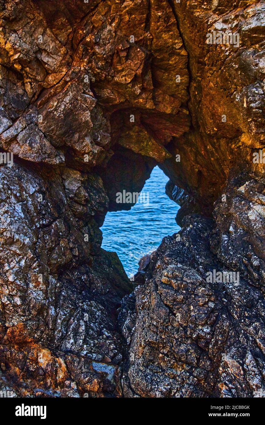 Ocean view seen through tunnel of sharp rocks Stock Photo - Alamy