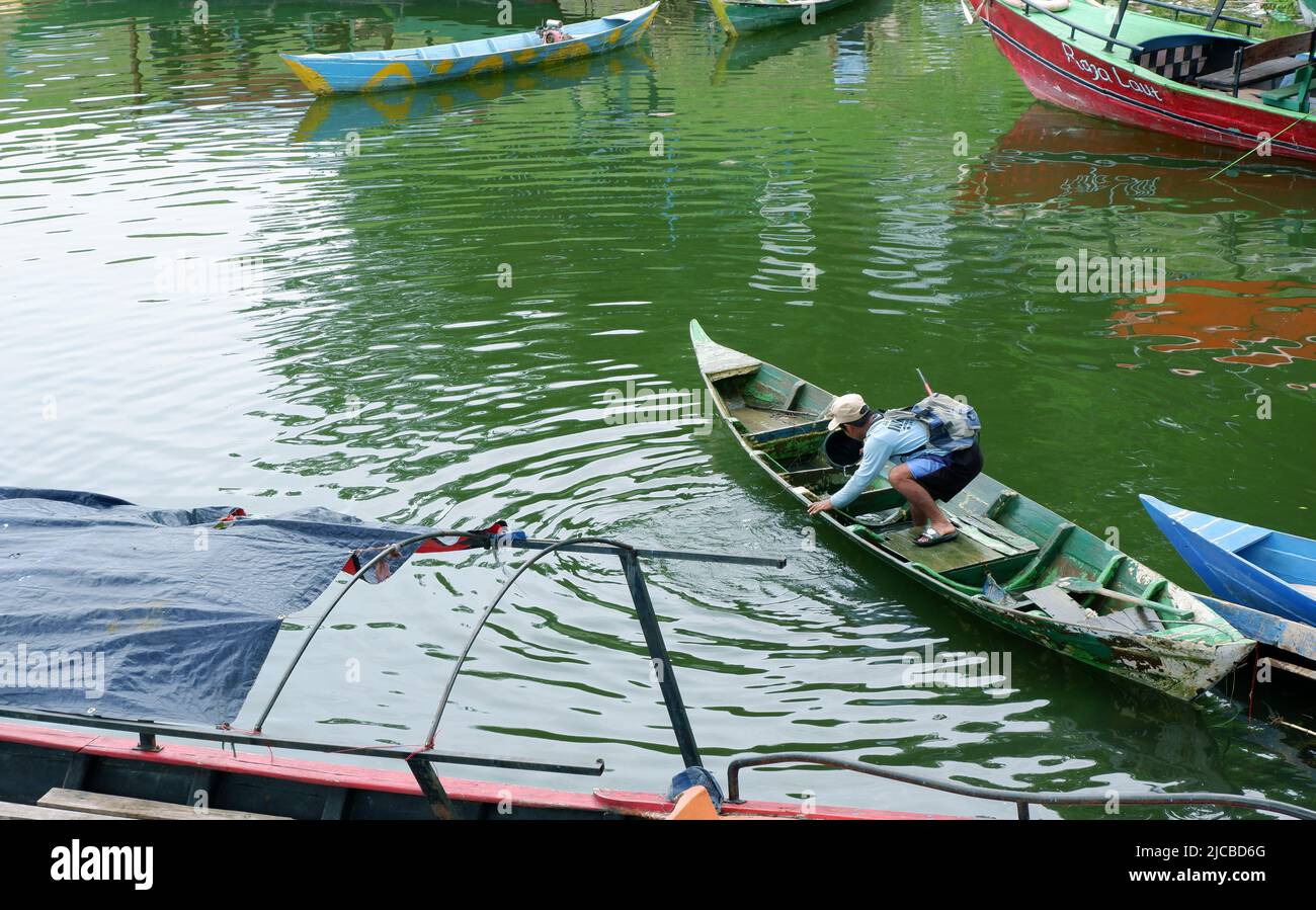 A male fisherman cleaning his boat. These fishermen return home after ...