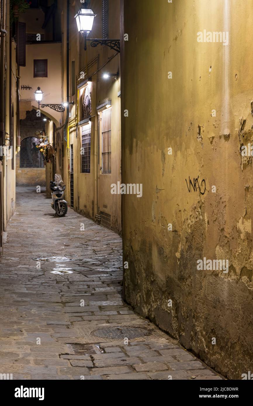 Time-worn narrow dead-end street lit up by streetlights with parked ...