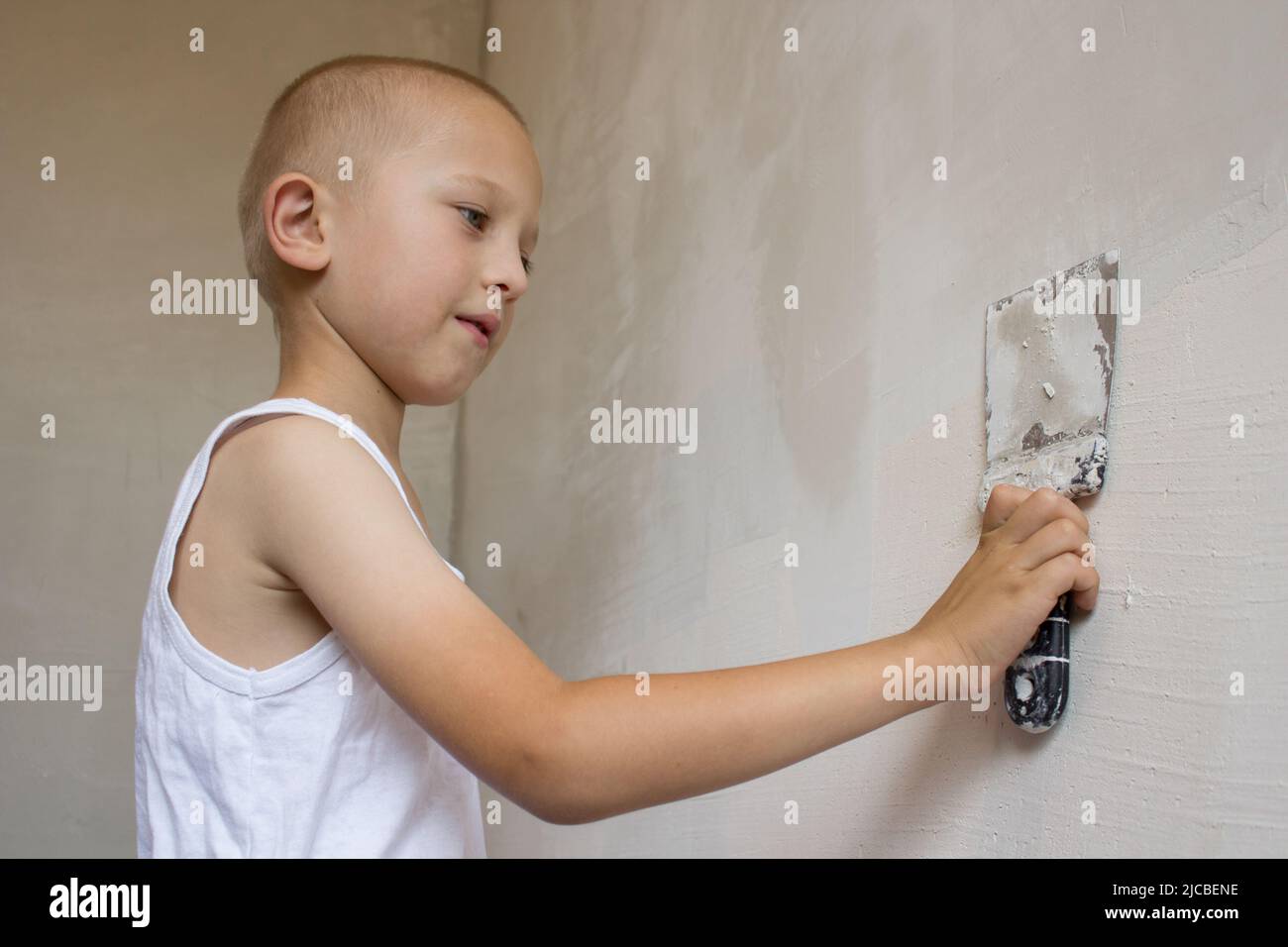 Little boy repairs wall with spackling paste Stock Photo - Alamy