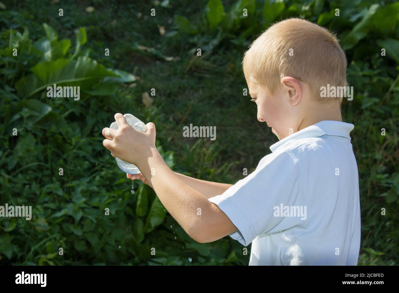 Boy pouring clean water from a bottle on the ground Stock Photo - Alamy