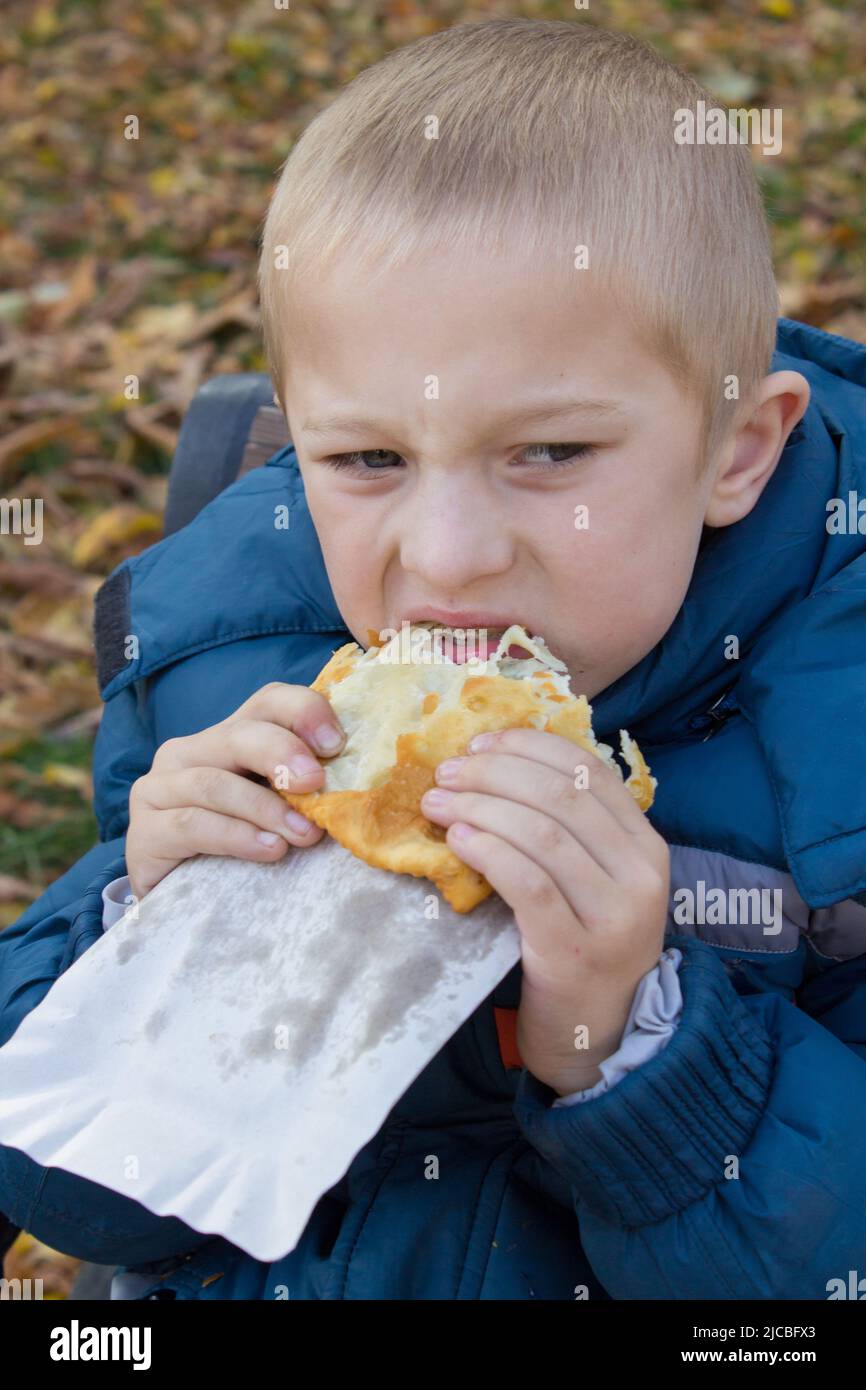 close-up of a boy biting big delicious pasties Stock Photo - Alamy