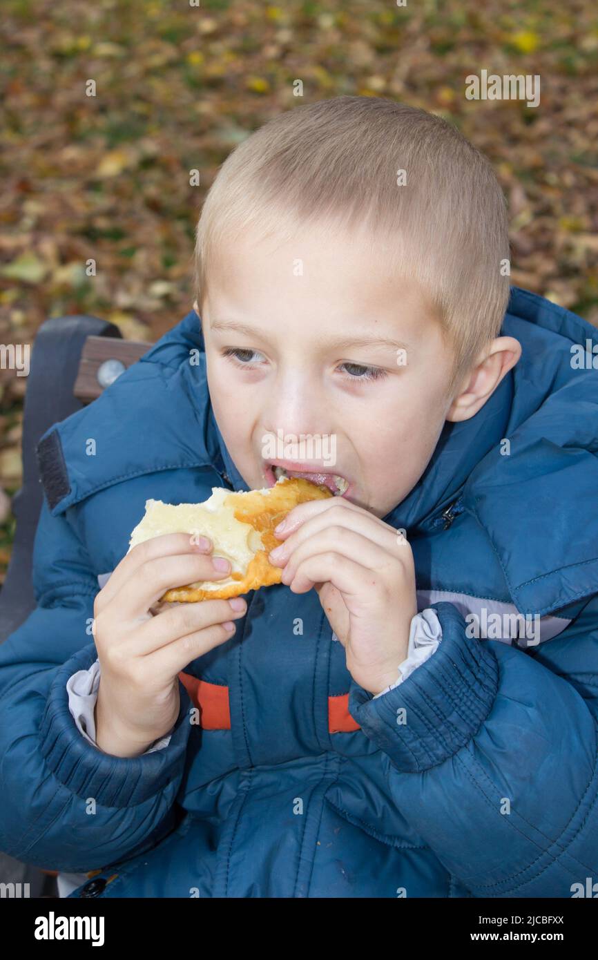 Hungry boy eating a piece of bread in the cold autumn Stock Photo - Alamy
