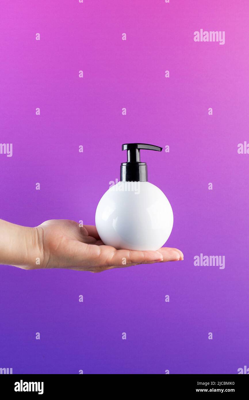 Mockup of a white dispenser with a cosmetic product in a woman's hand ...