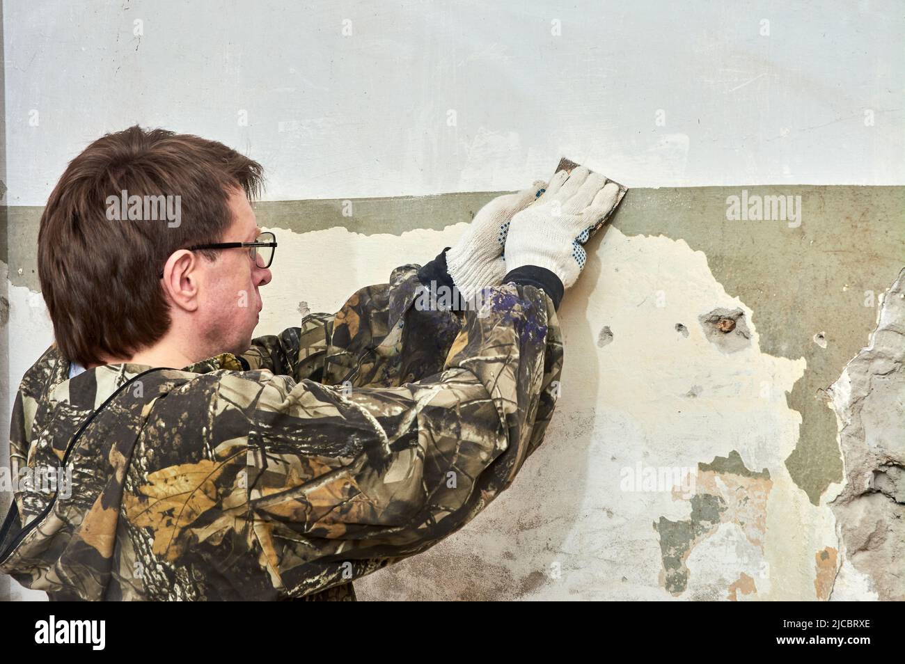 removing paint from the wall with a scraper, repairing the room Stock ...