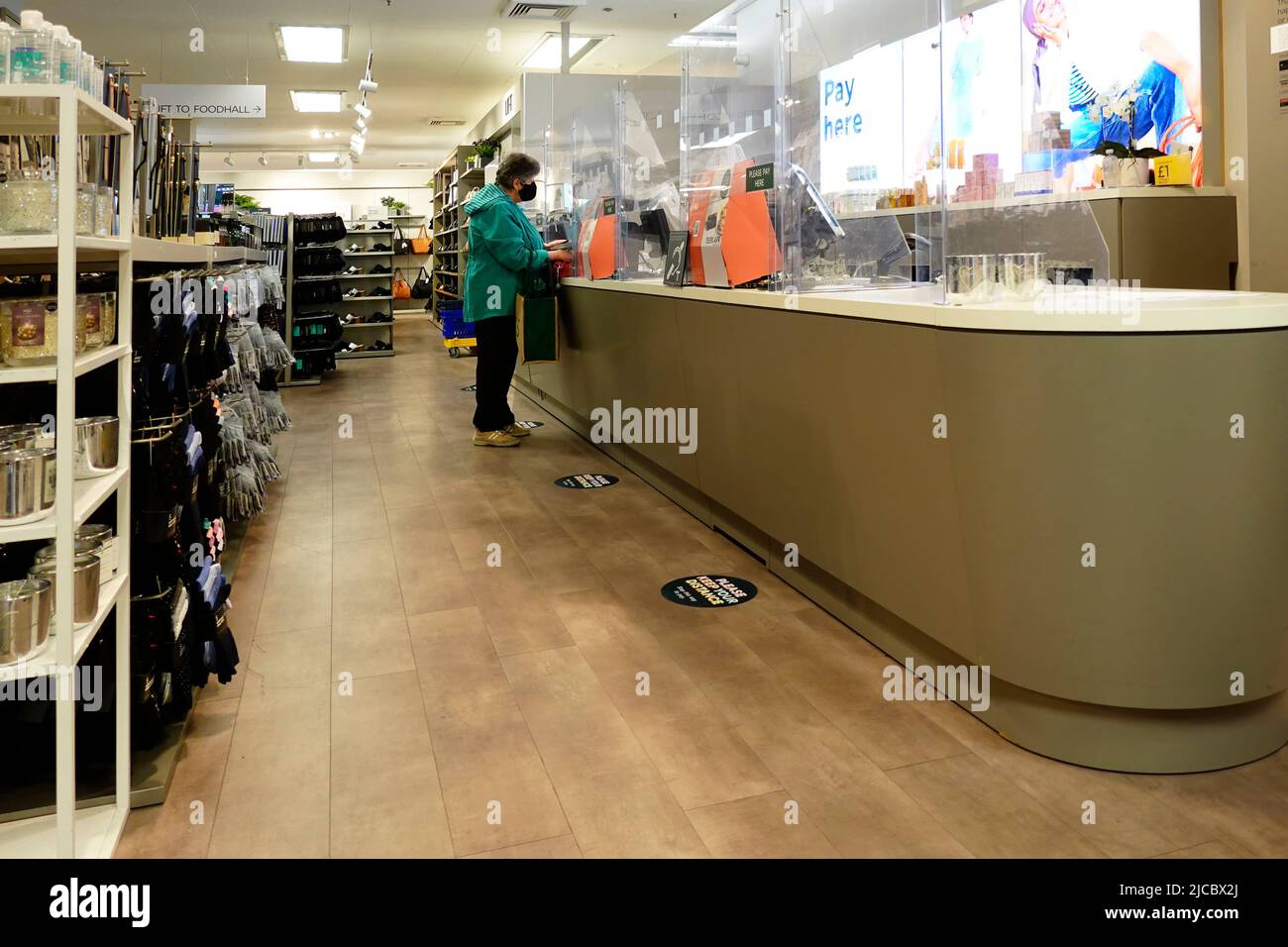 Mature senior pensioner OAP woman standing & being served at long M&S ...