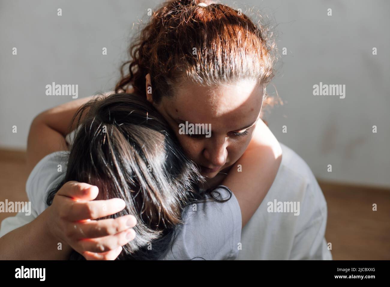 Portrait of abused family. Young sad woman holding girl, consoling ... Portrait of abused family. Young sad woman holding girl, consoling ...