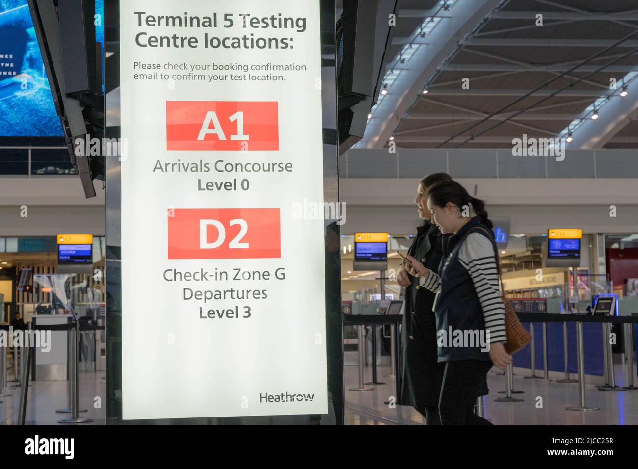 passengers walk toward the signage to covid-testing centre in London ...