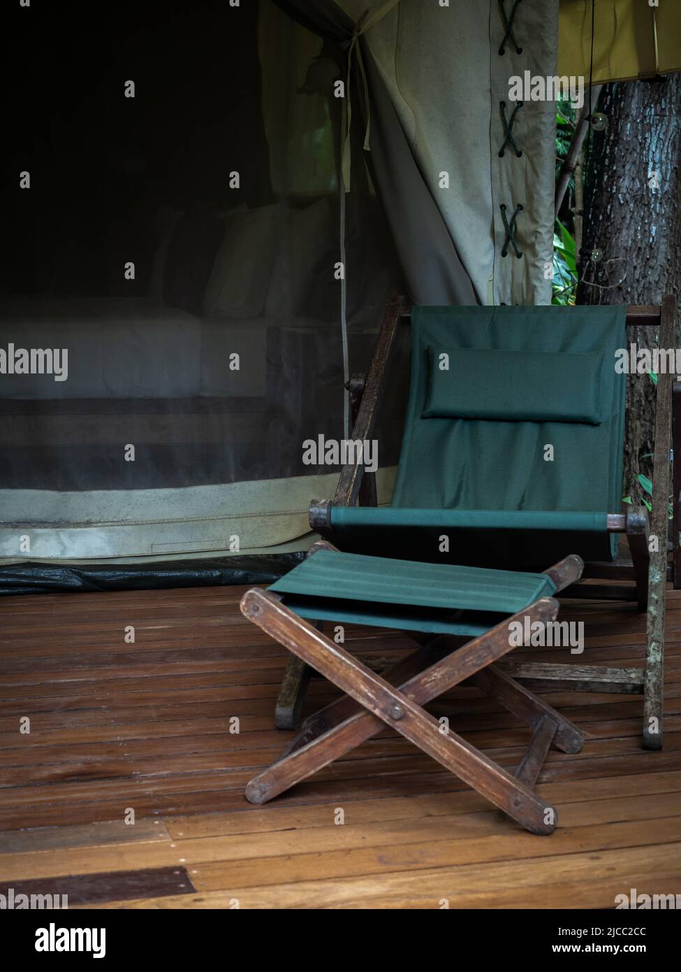 Empty camping wooden chair with green fabric seat and footrest on the ...