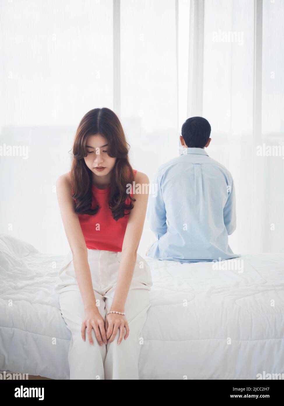 The anxiety of Asian couple lovers on the bed. Sad young woman and man ...
