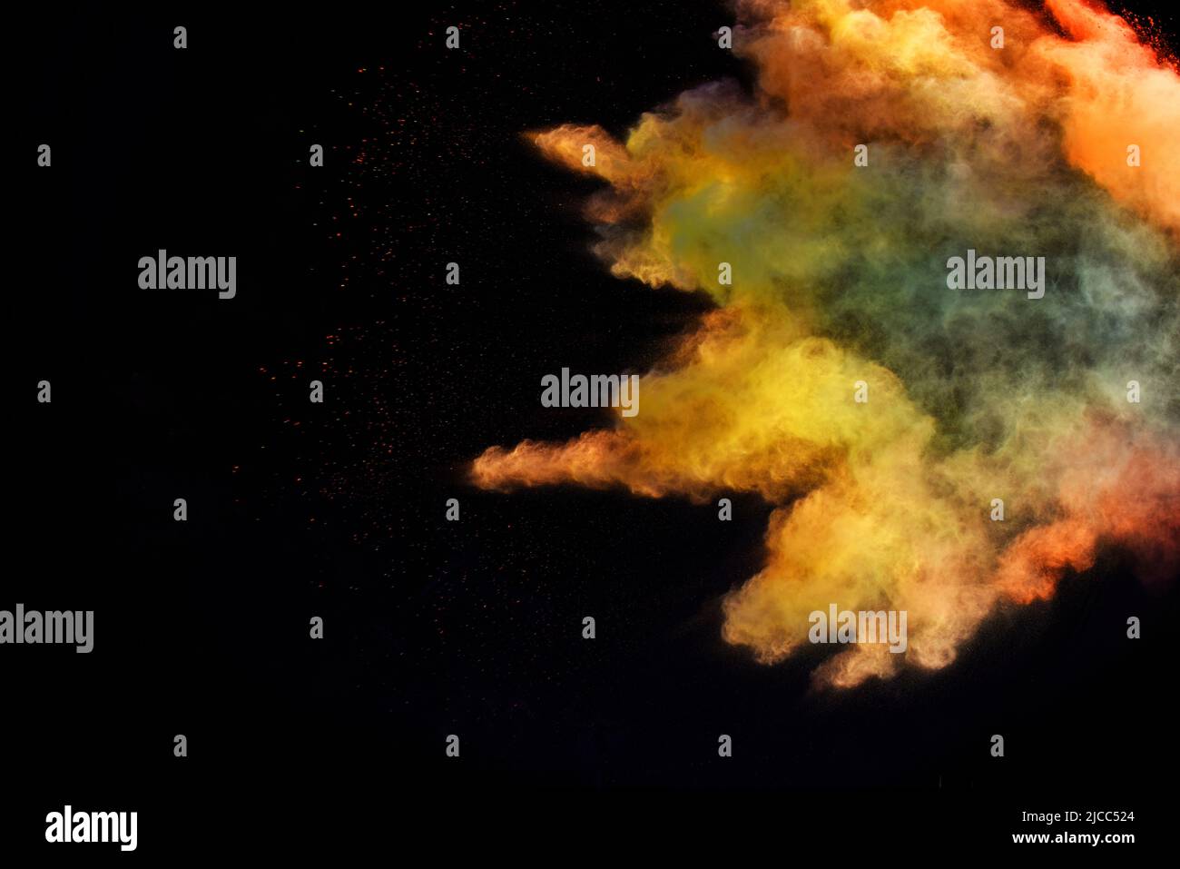 Vivid multi-coloured forms of powder paint explode in front of a black ...