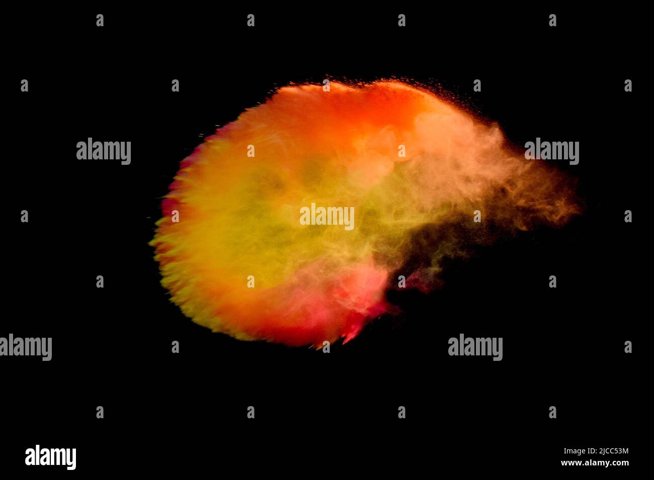 Vivid multi-coloured forms of powder paint explode in front of a black ...