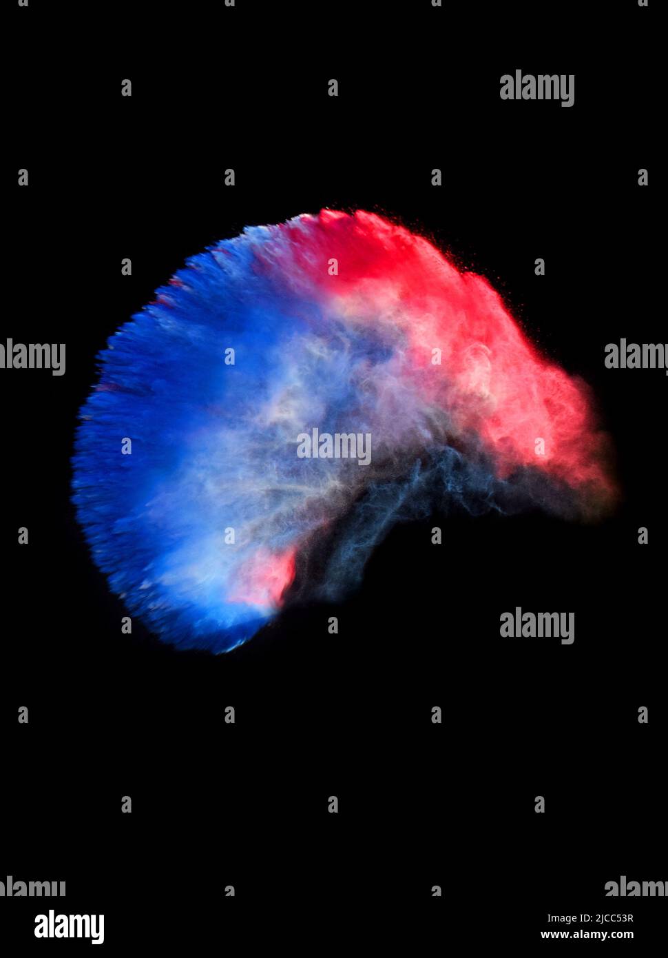 Vivid multi-coloured forms of powder paint explode in front of a black ...