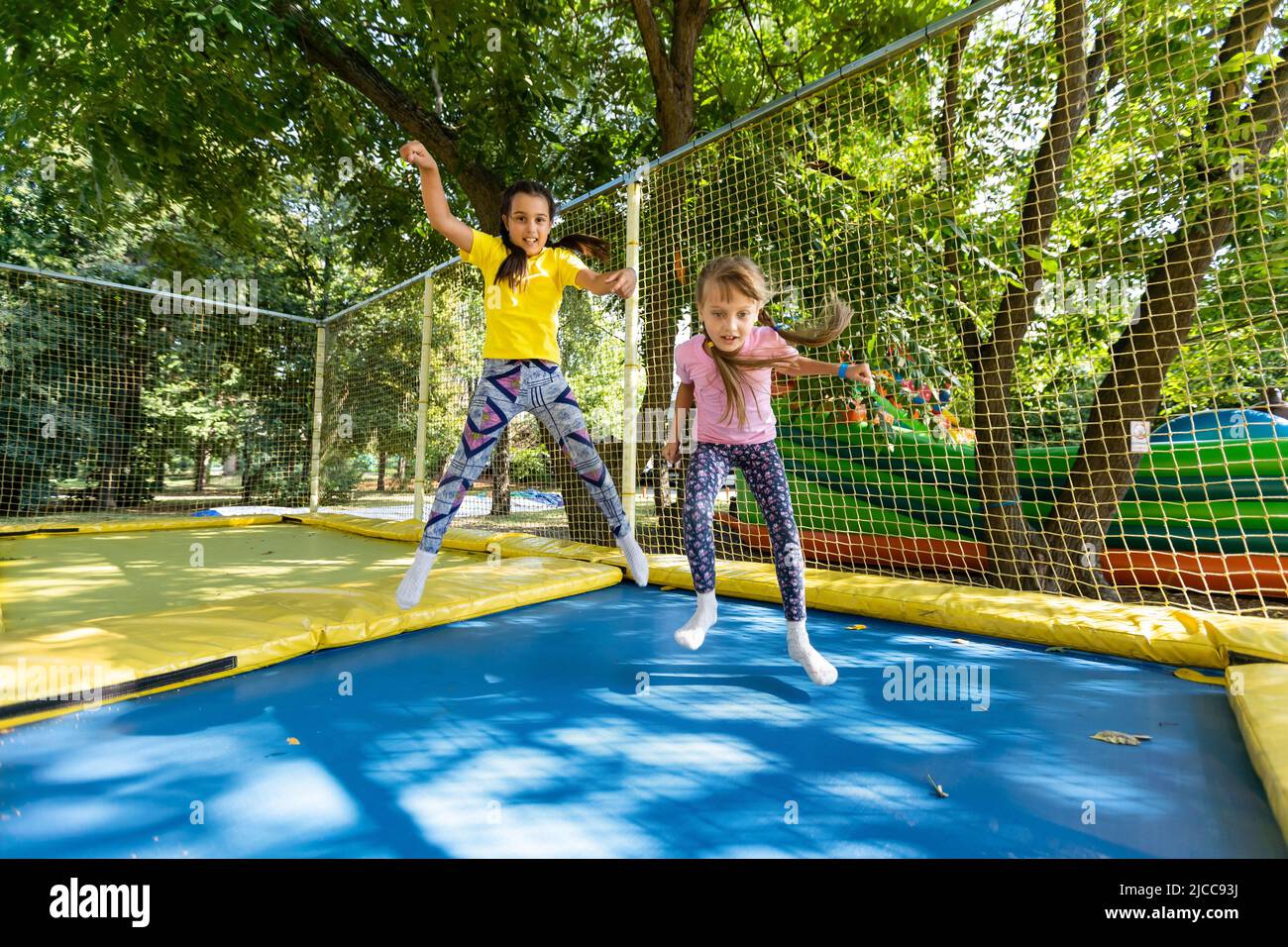Little pretty girls having fun outdoor. Jumping on trampoline in ...