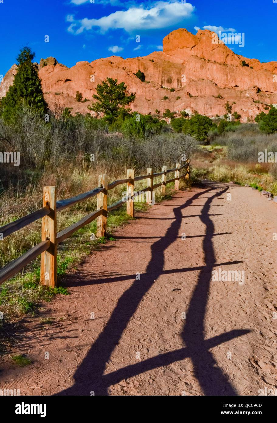 A wooden fence with a shadow from the sun on a background of red ...