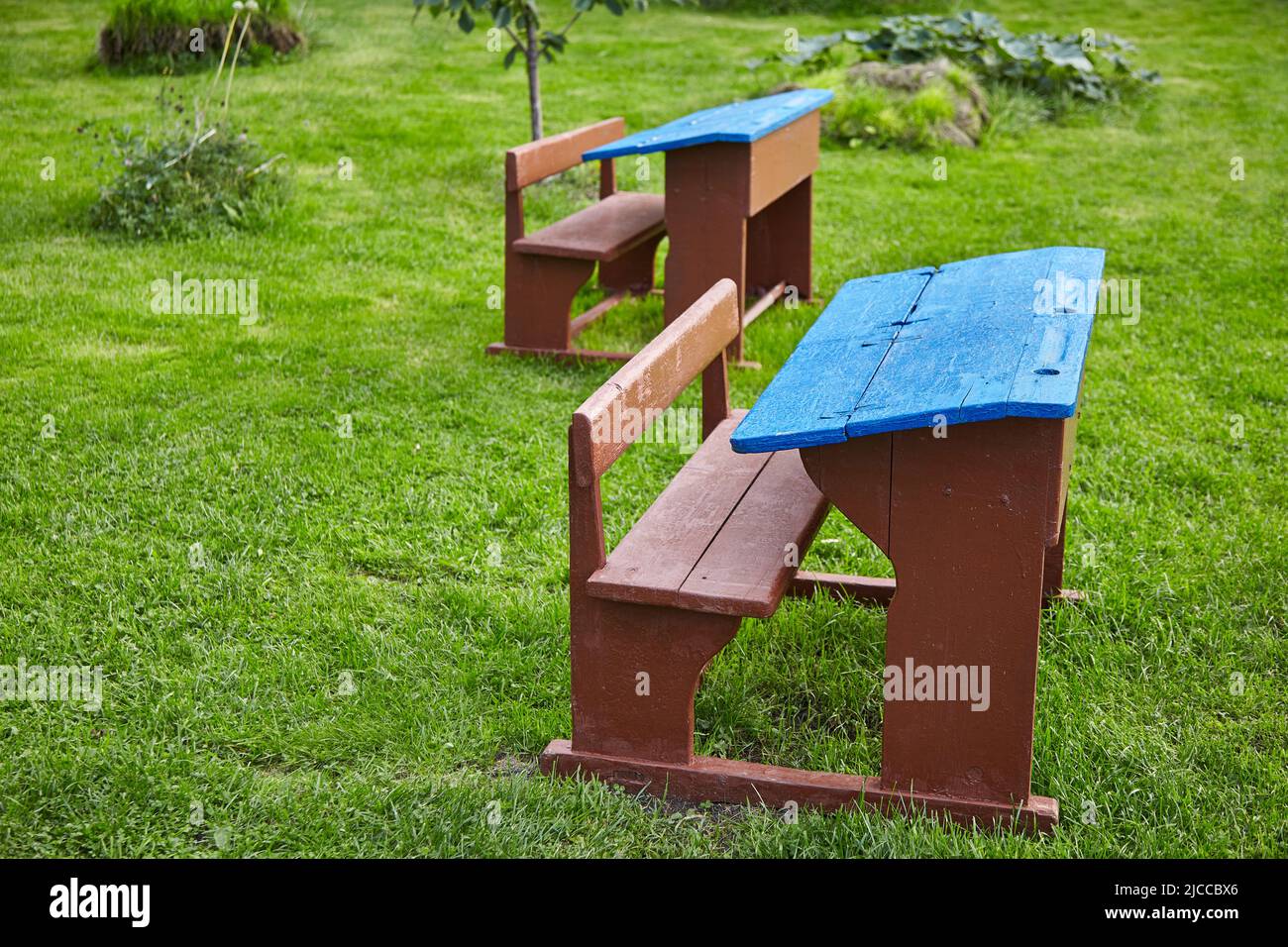 Old vintage empty school desks on a green lawn. Remote and distance ...