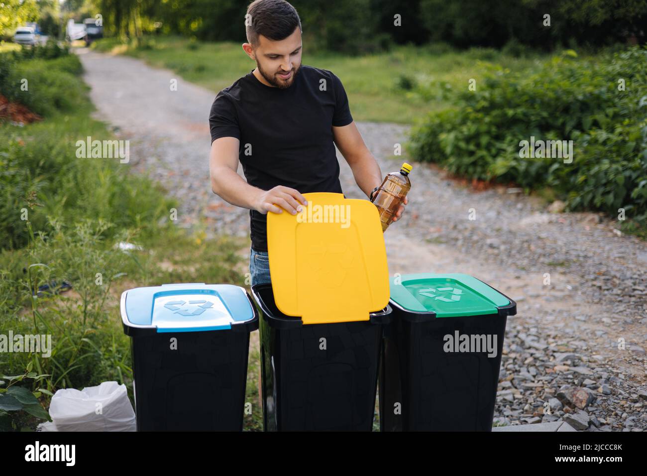 Man throwing plastic bottle into recycling bin on back yard. Different ...