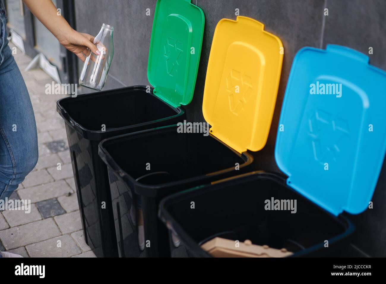 Close-up of female throwing glass bottle in recycling bin. Different ...