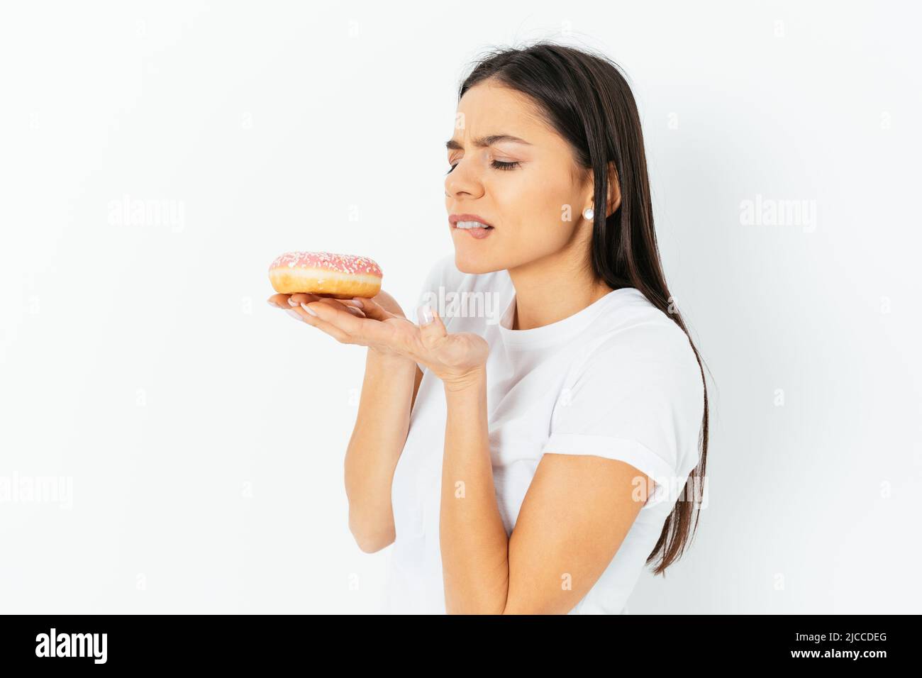 Portrait of young woman resist to eat junk food, desiring to eat donut ...
