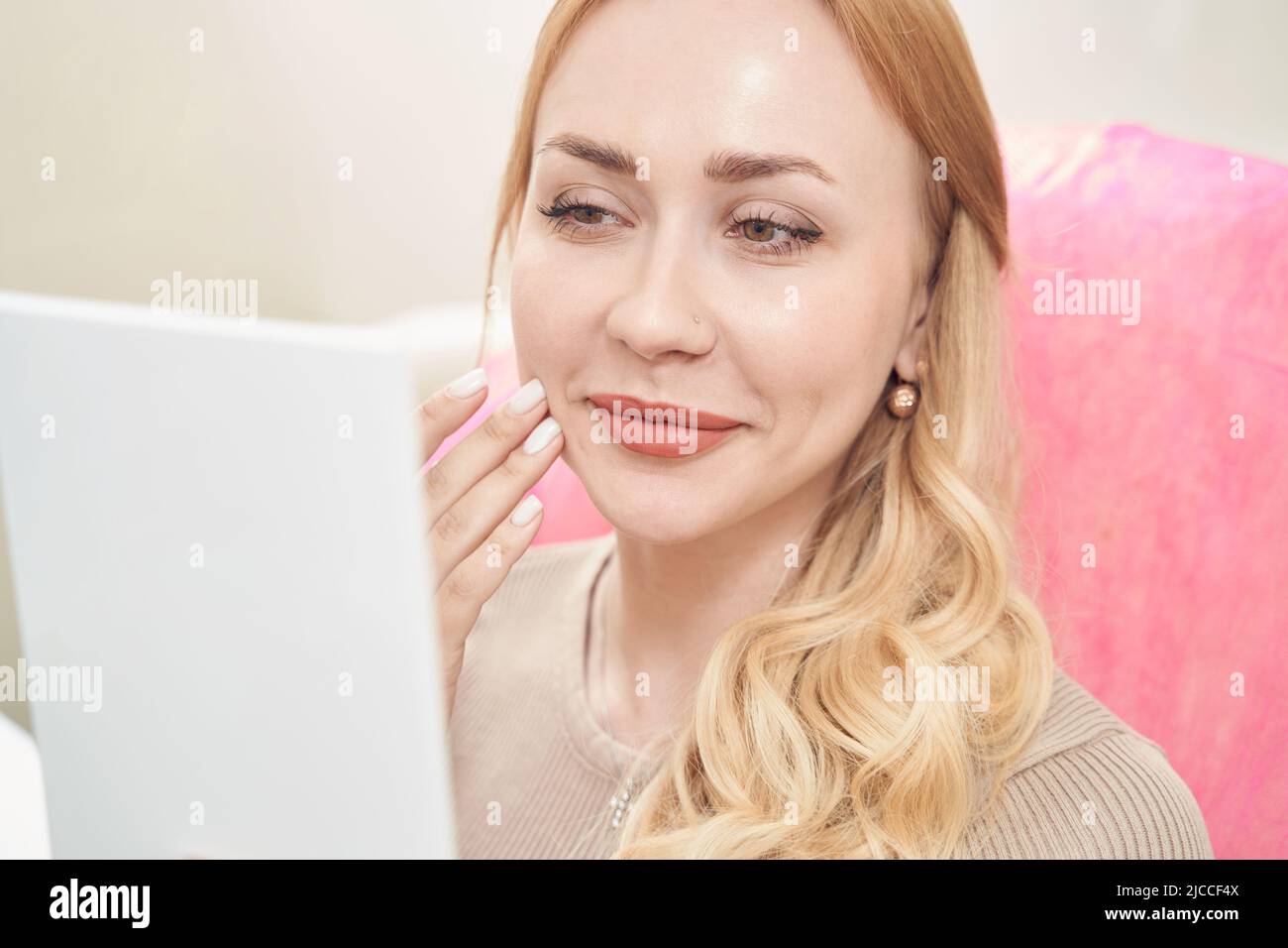 Beautiful Caucasian female is staring at her reflection in the mirror ...