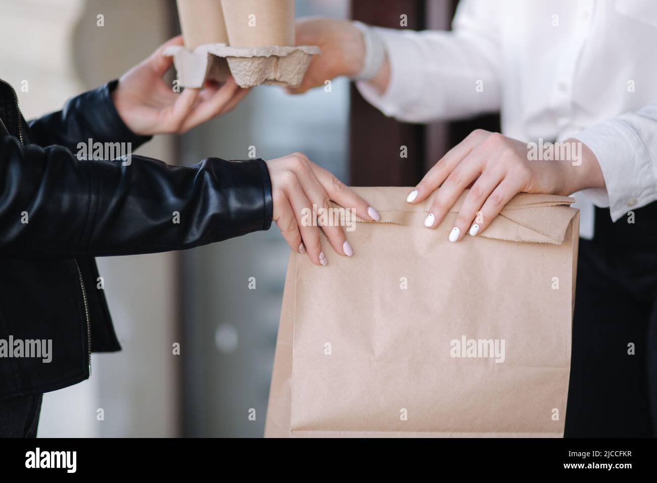 Customer in face mask stand outdoors and take package with coffee and ...