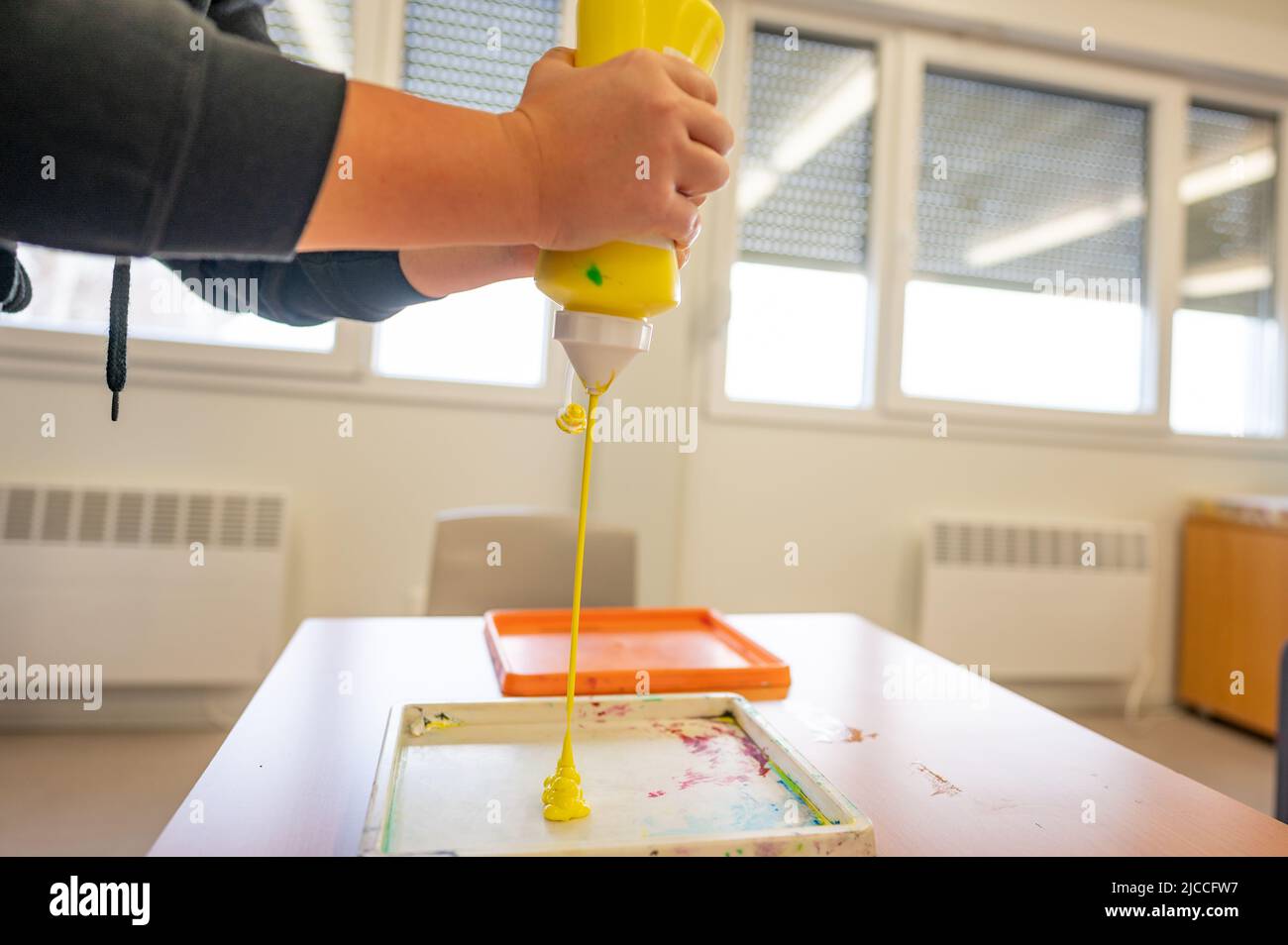 Worker squeezing yellow paint from tube into tray to prepare it for ...