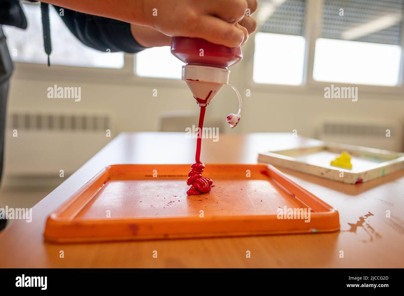 Worker squeezing red paint from tube into tray to prepare it for ...