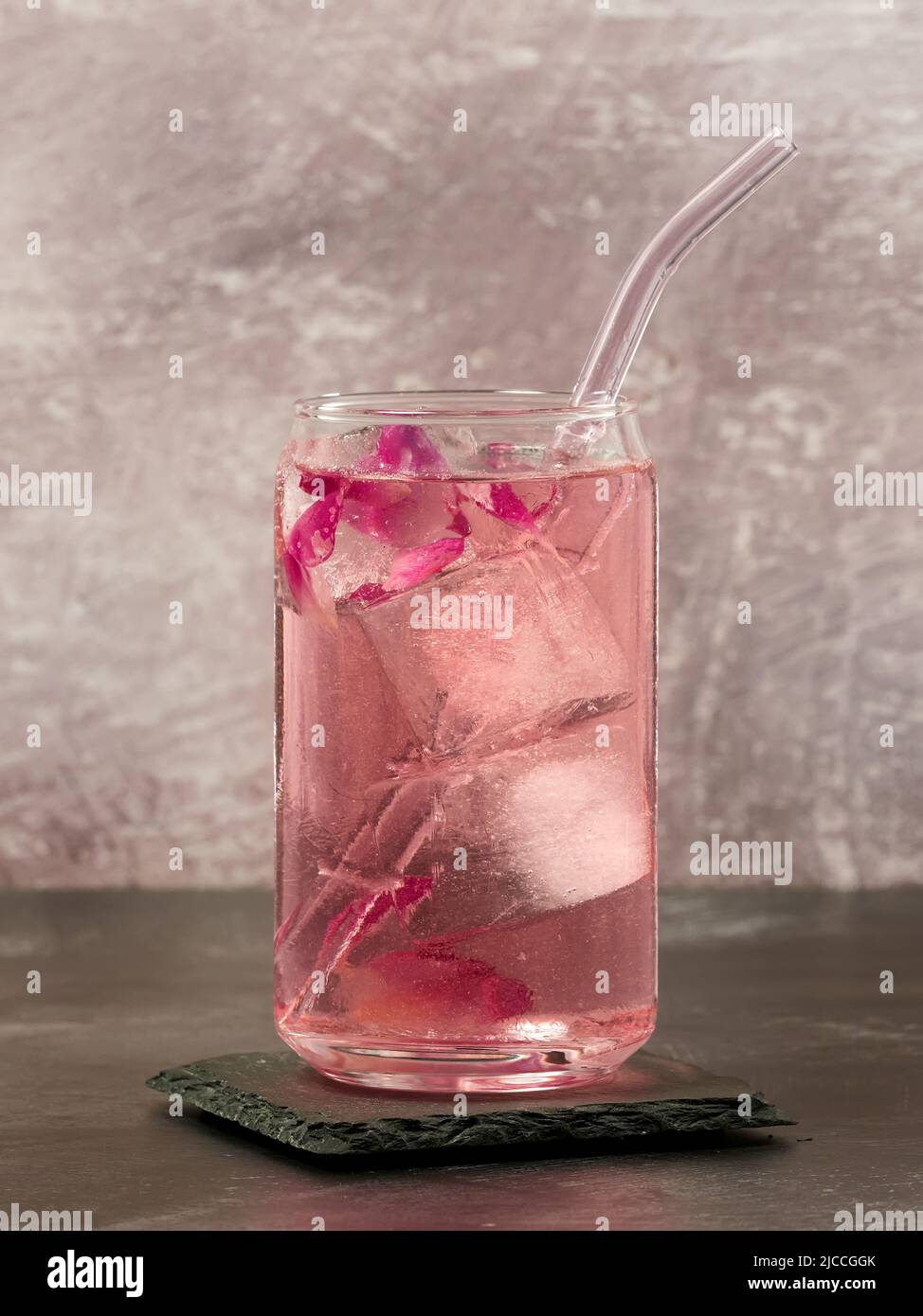 A glass of pink gin and rose lemonade on a light pink background, top ...