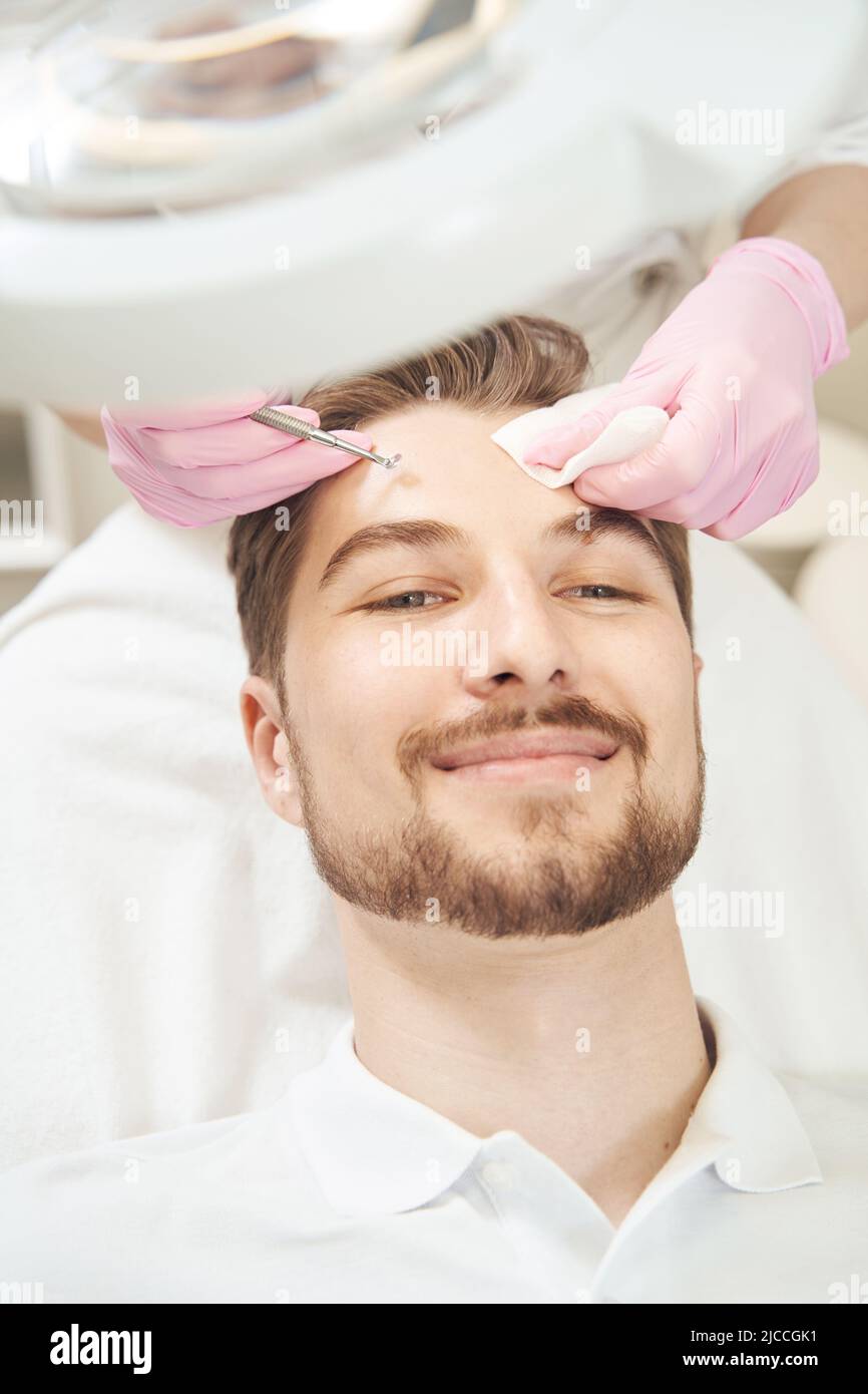 Male enjoying uno spoon skin treatment in aesthetic medical center ...