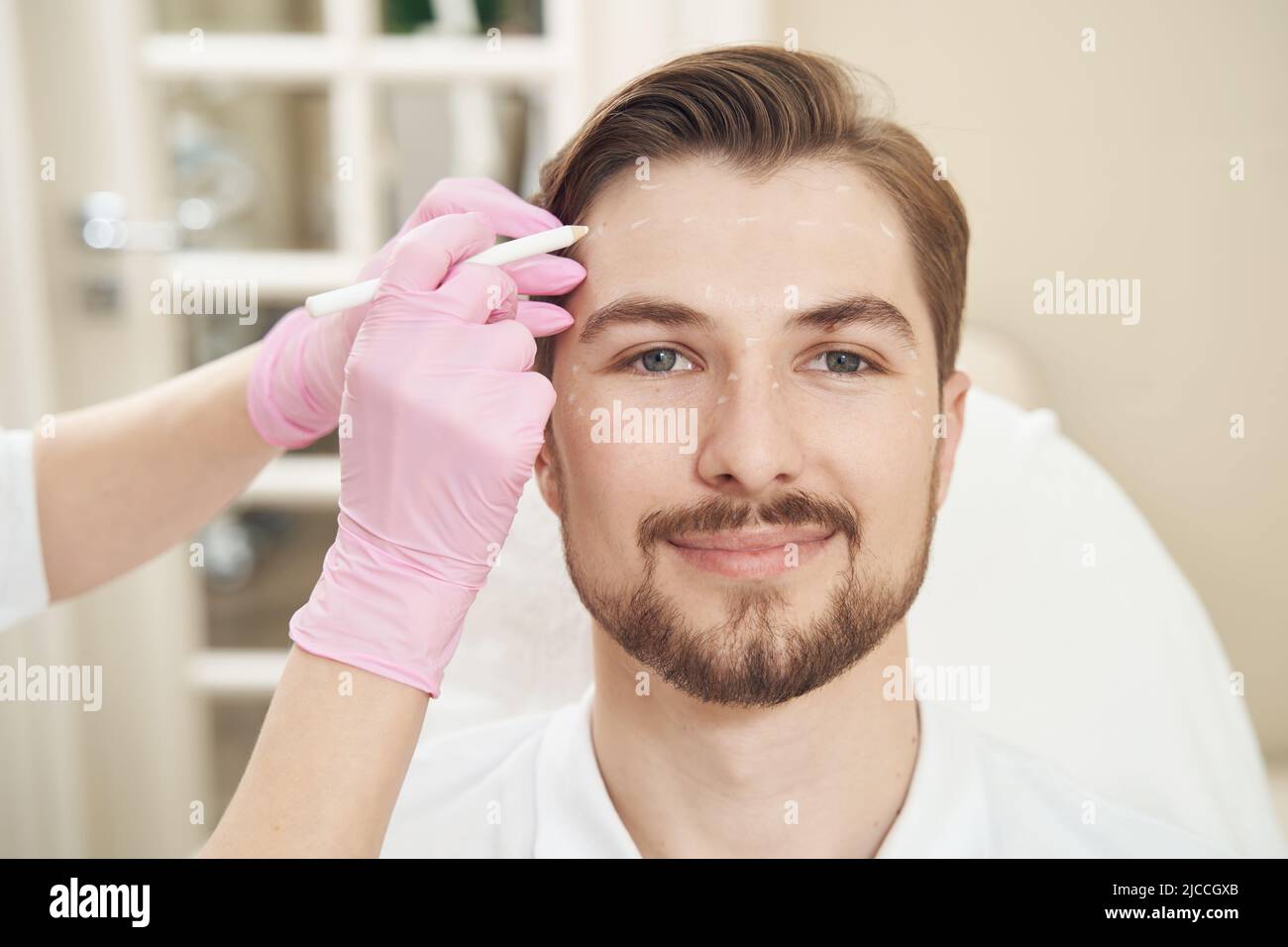 Cosmetologist drawing marks on male face with contour pencil Stock ...