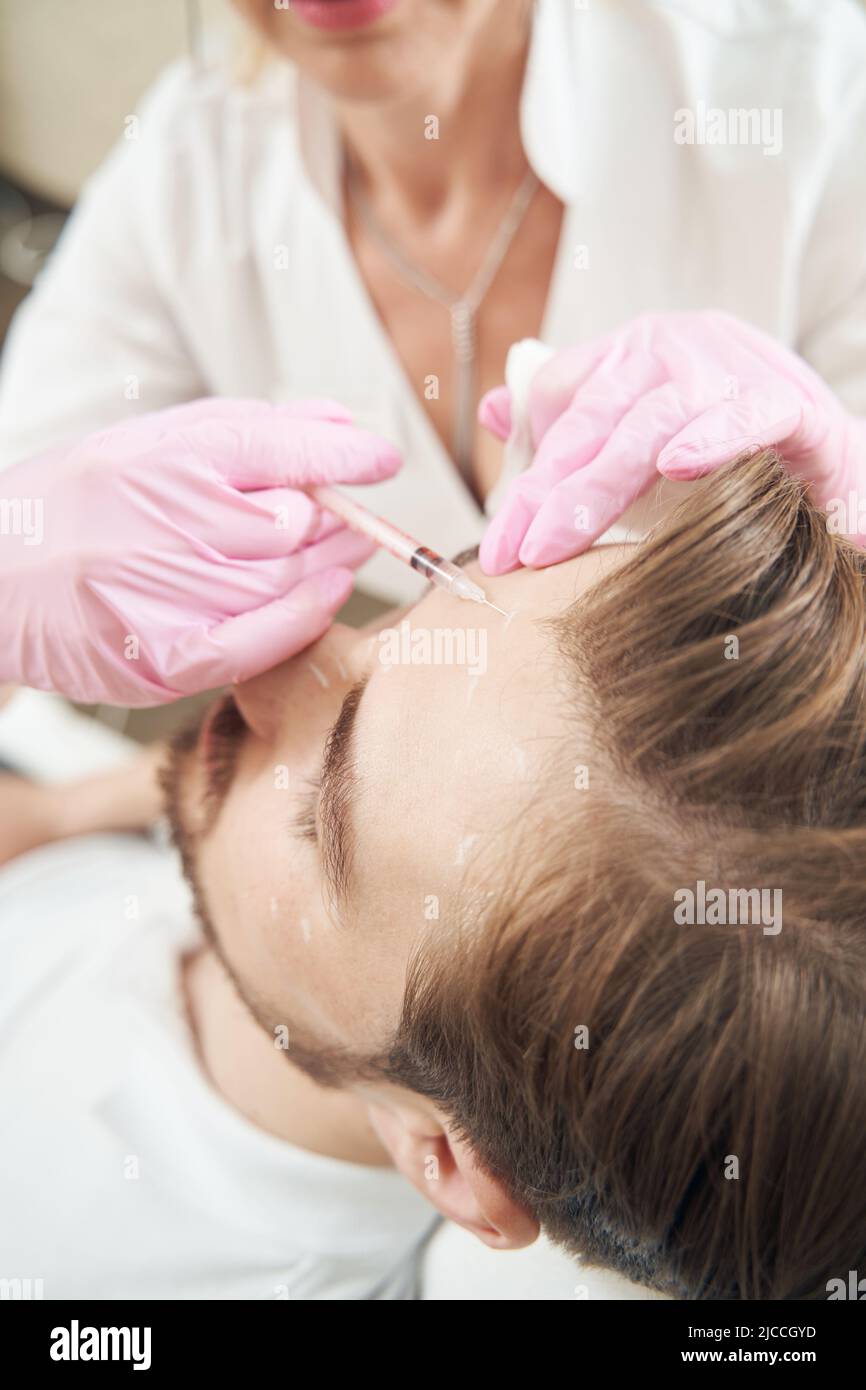 Injection into forehead of male beauty shop client Stock Photo - Alamy