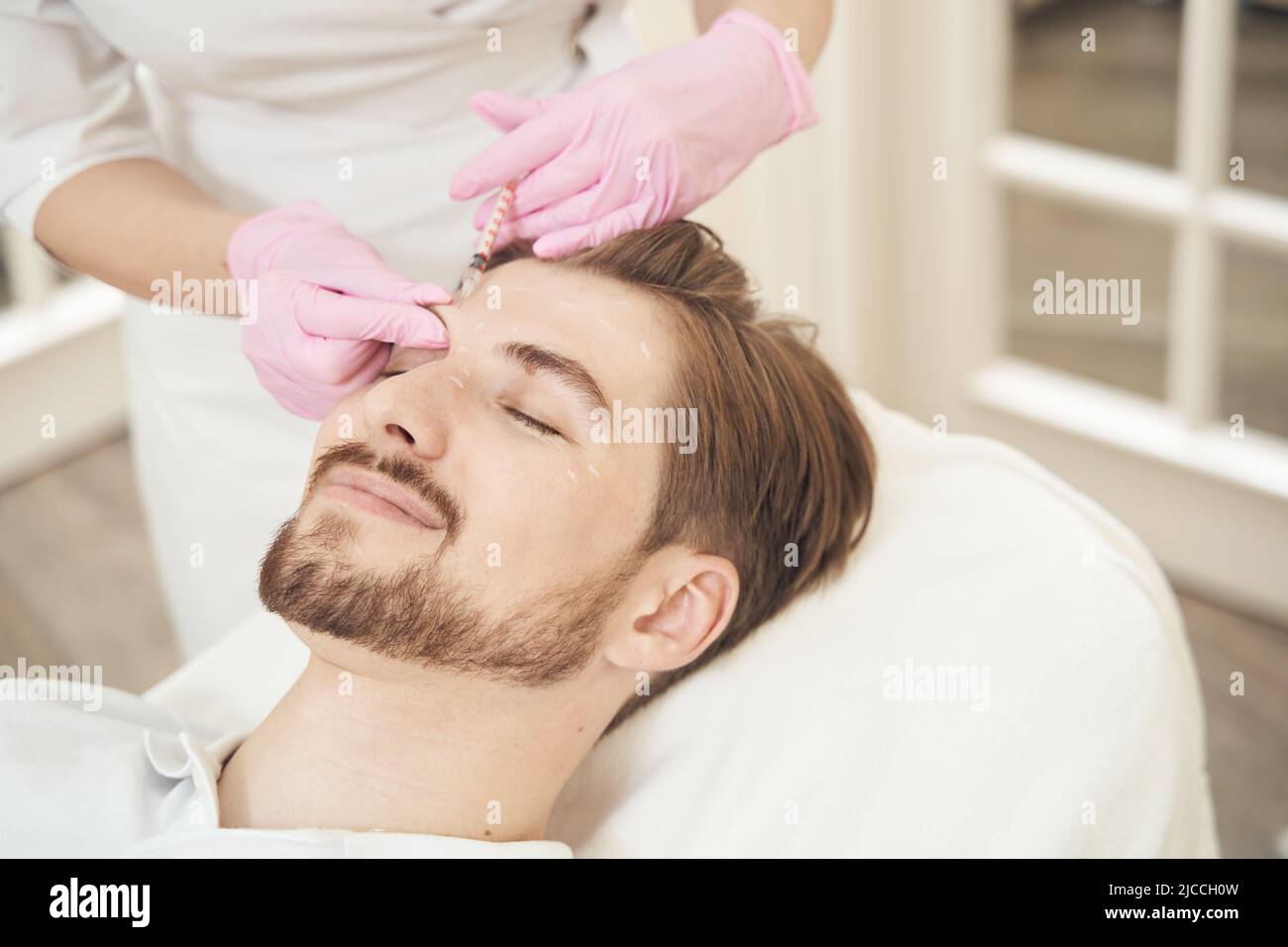 Male on couch enjoying anti-aging injection to his head Stock Photo - Alamy