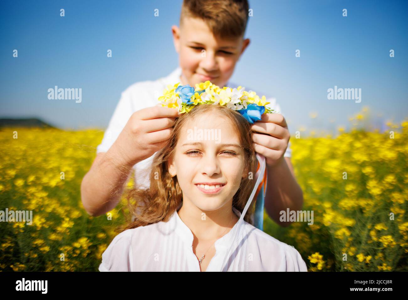 Kind caring teenage brother carefully puts on floral Ukrainian bright ...