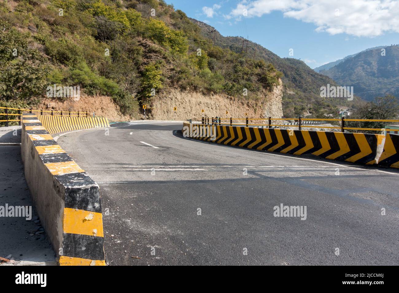 A wide-angle shot of an all-weather asphalt road with yellow concrete ...