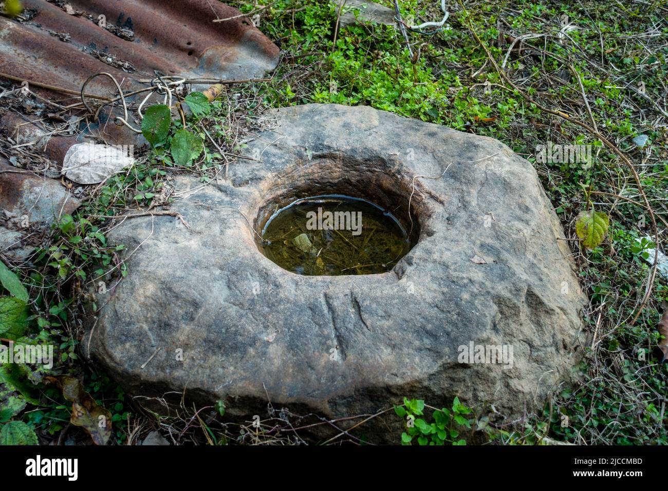 A close up shot of a round pothole on a stone filled with rain water ...