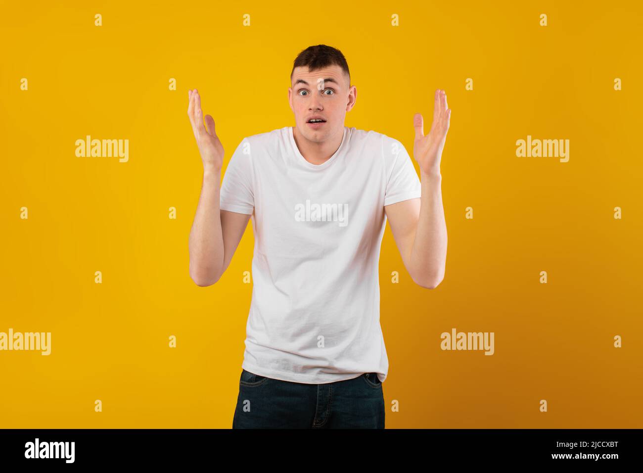 Overwhelmed Guy Looking At Camera In Confusion Over Yellow Background ...