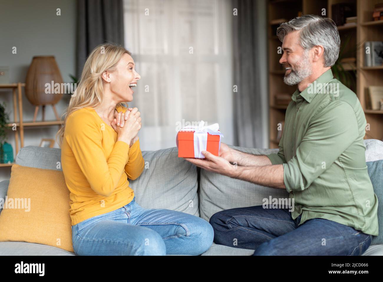 Loving middle aged man giving present to his excited wife at home Stock ...
