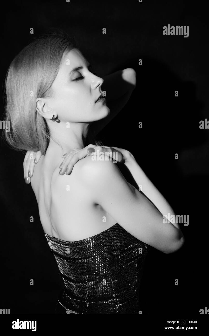 Beauty portrait of a woman in black dress with bare shoulders, blond ...